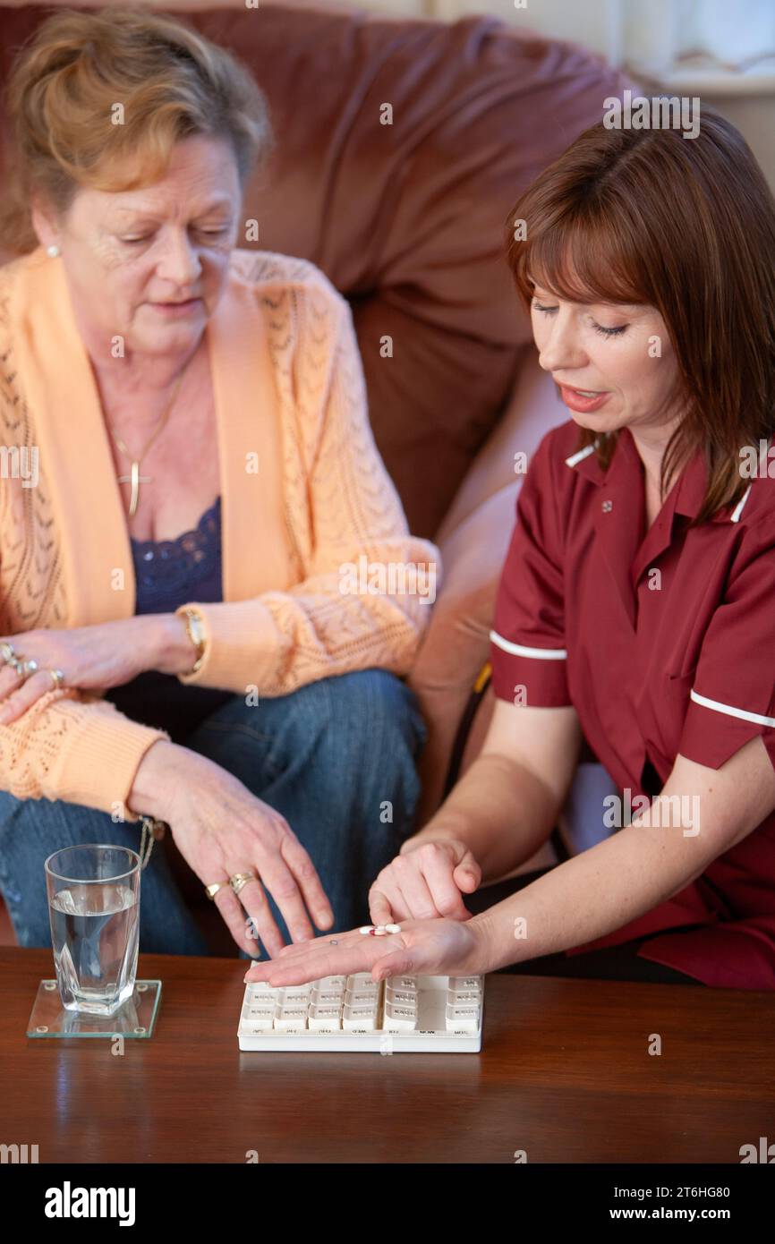Help the Aged: Medication. A visiting carer explaining to her senior ...