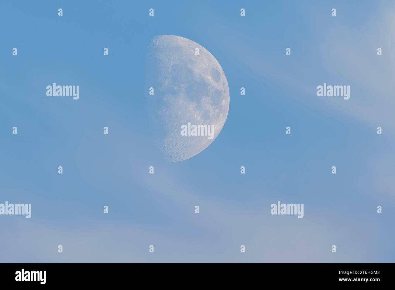 A partial moon sphere with visible craters moves across the blue sky ...