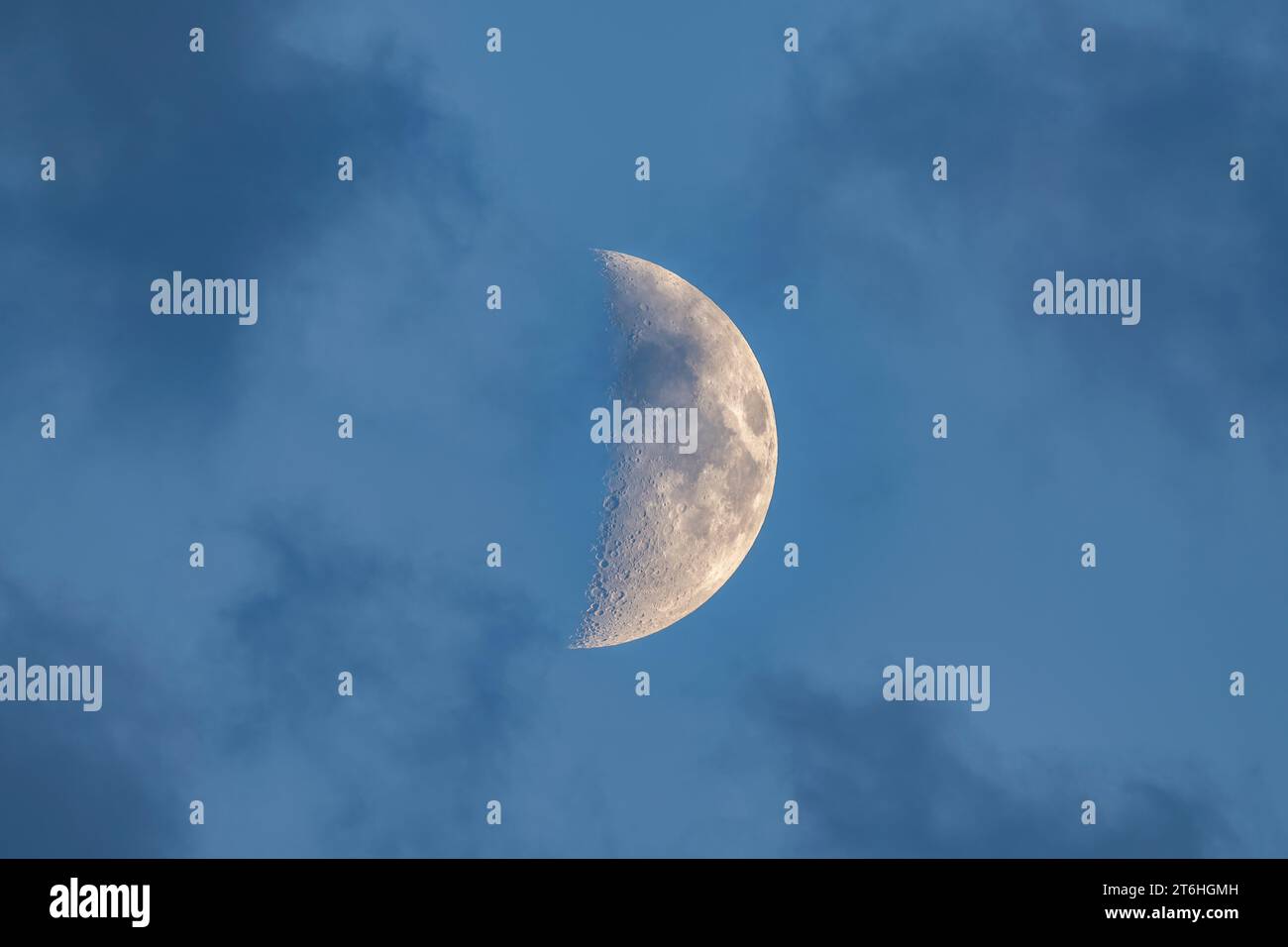 A partial moon sphere with visible craters moves across the blue sky ...