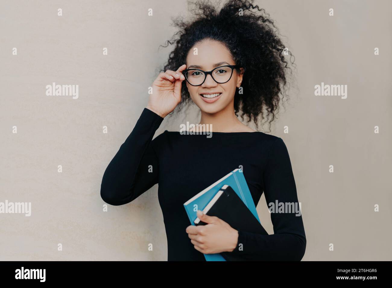 Smart young professional adjusting glasses, holding a tablet, with a ...