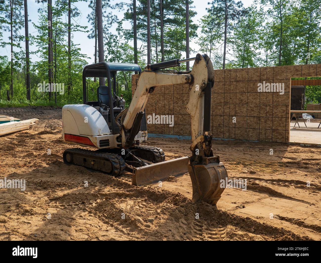 Mini excavator parked on the dirt outside a new home building project ...