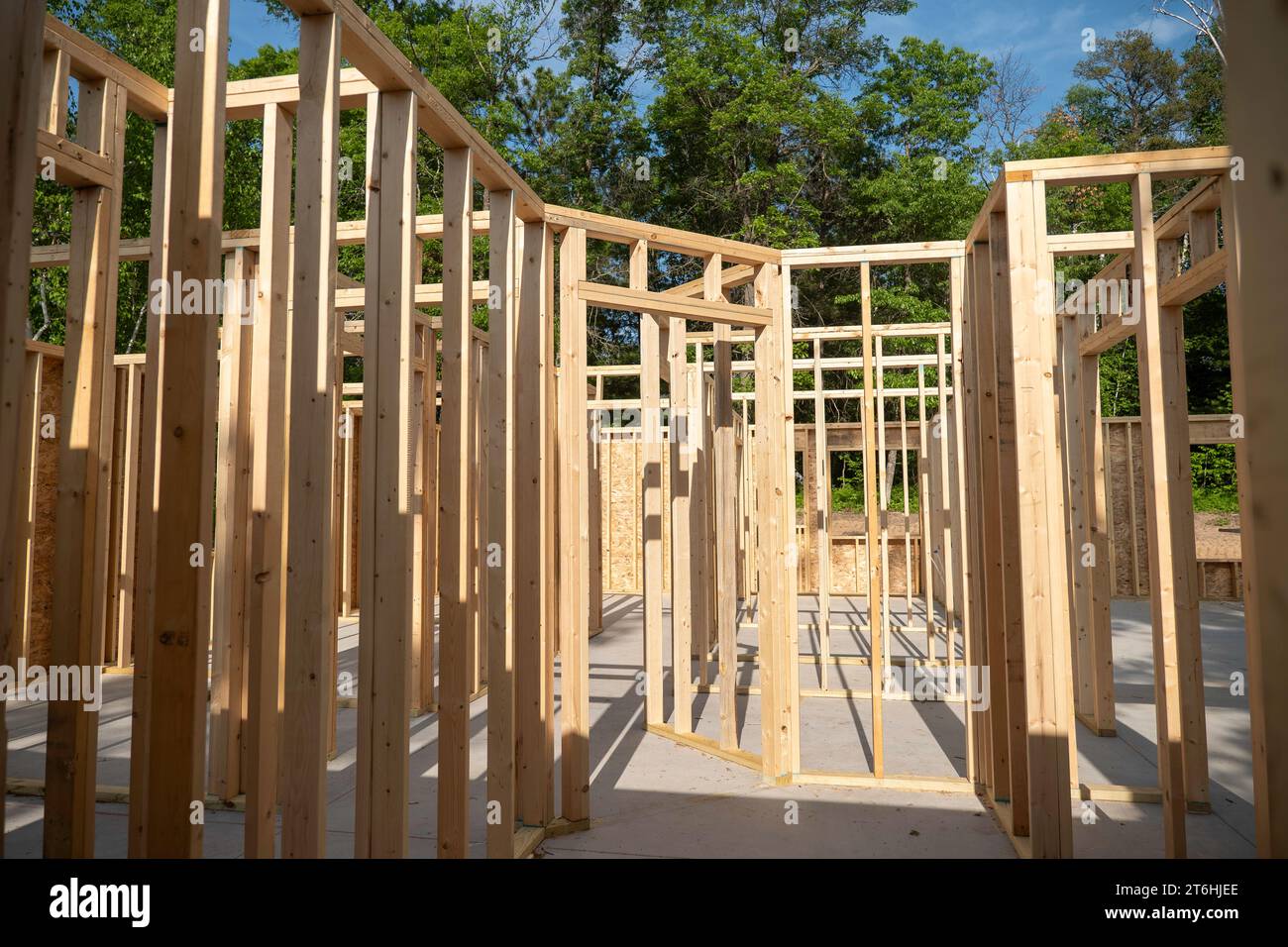Closeup of wood framing studs at new home construction work site in sunshine with shadows, with ...