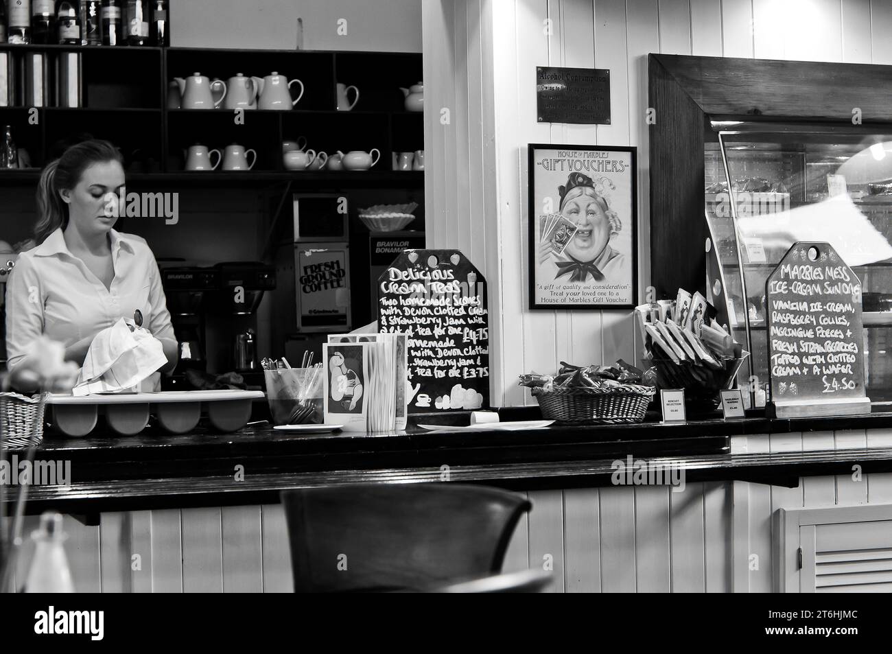 A waitress drying cutlery behind the counter of a catering ...