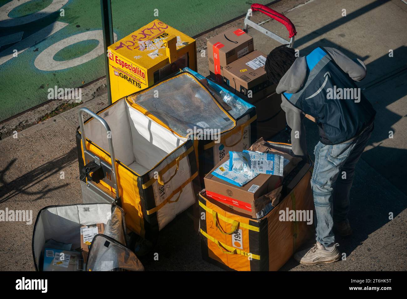 An Amazon worker sorts deliveries on the sidewalk for distribution in ...