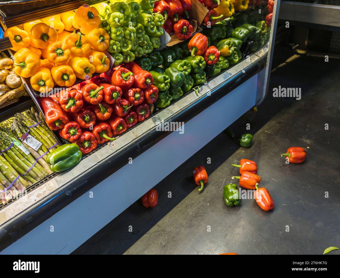 A display of peppers, some spilled, in the produce department of a ...