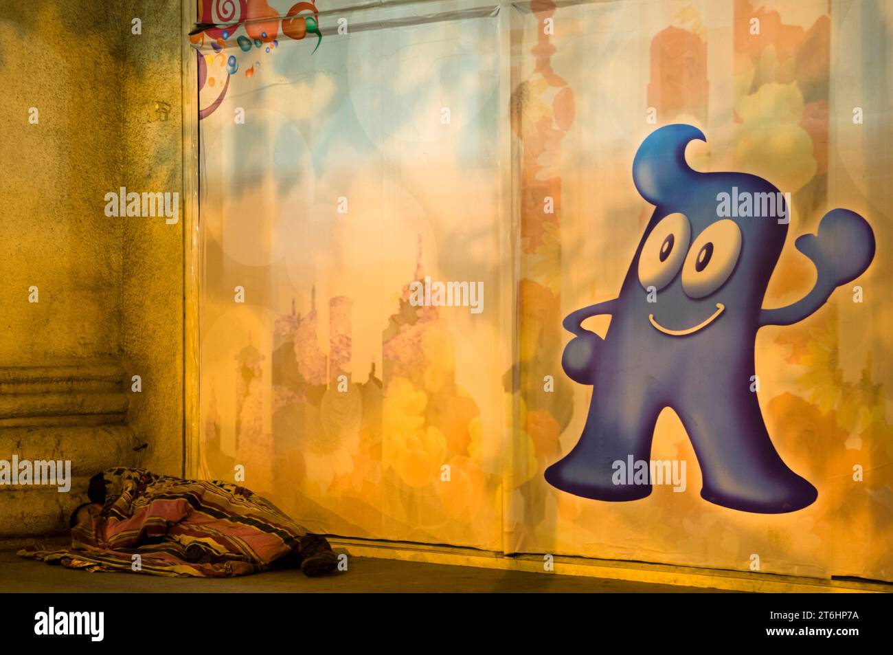 China, Shanghai, a homeless man sleeps on the street under a picture of ...