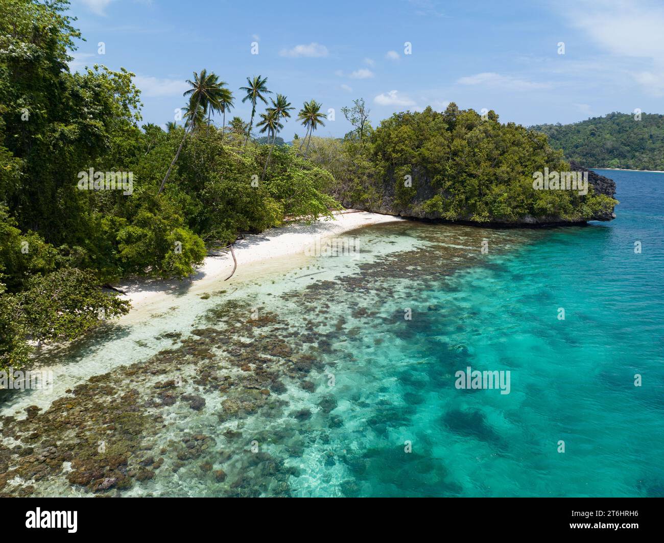 A shallow coral reef grows along the edge of a scenic island in Alyui ...