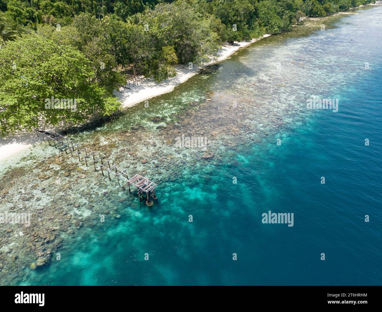 A shallow coral reef grows along the edge of a scenic island in Alyui ...