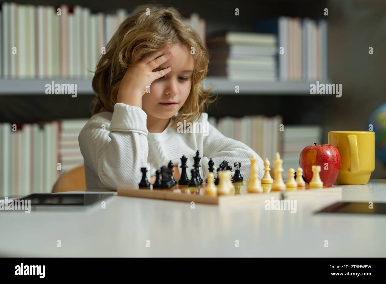Kid thinking of chess. Little kid play chess in school class. Child boy ...