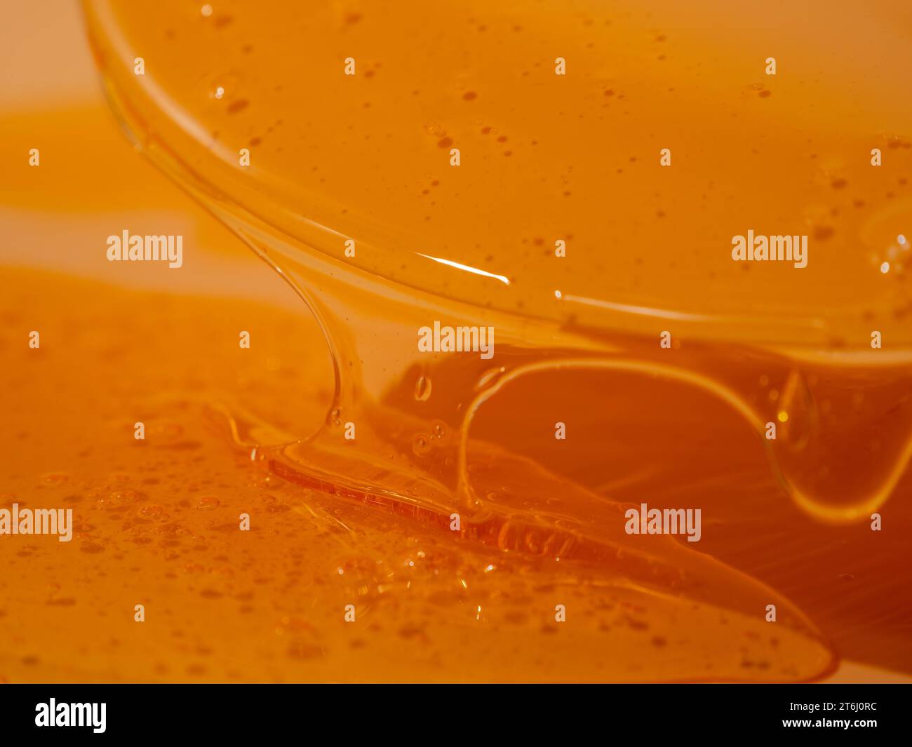 Liquid shower gel flows gracefully across a bright orange background ...