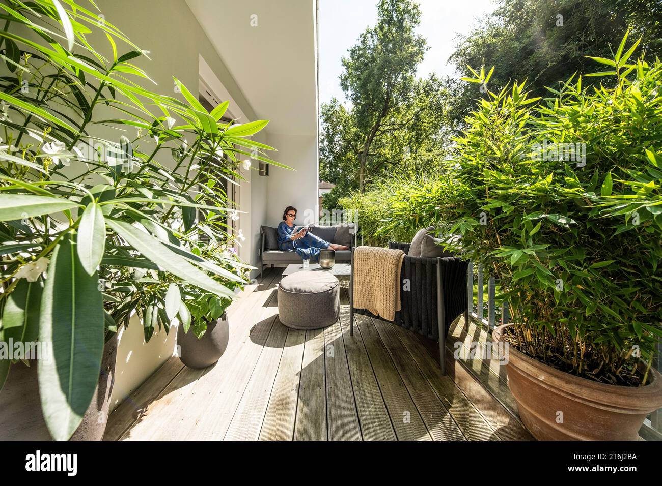 Woman sitting on the balcony with modern lounge furniture and reading a ...