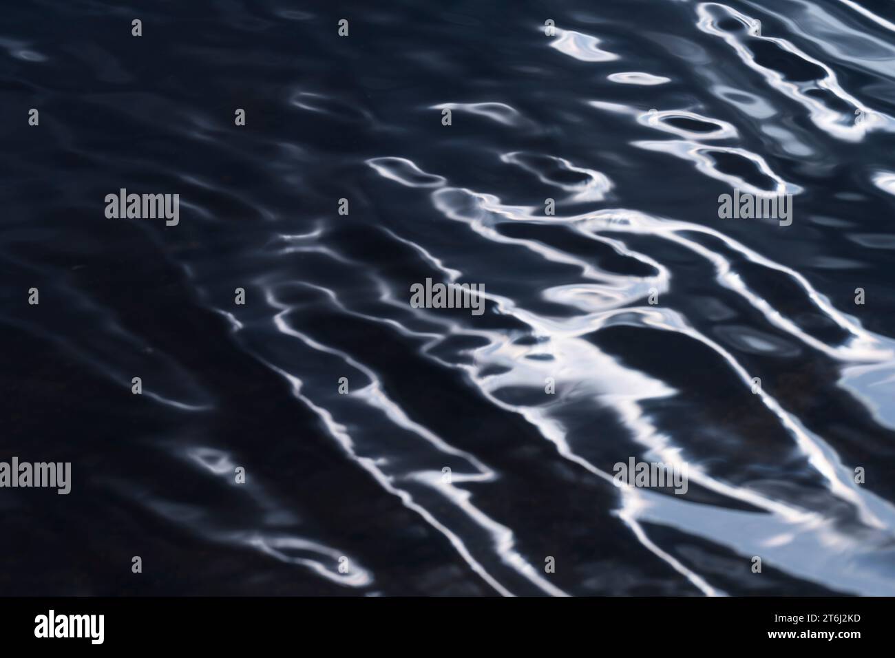 small waves and light reflections on the water surface of a lake ...