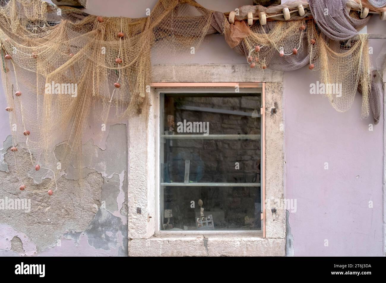 Weathered house facade with small window and fishing nets as decoration ...