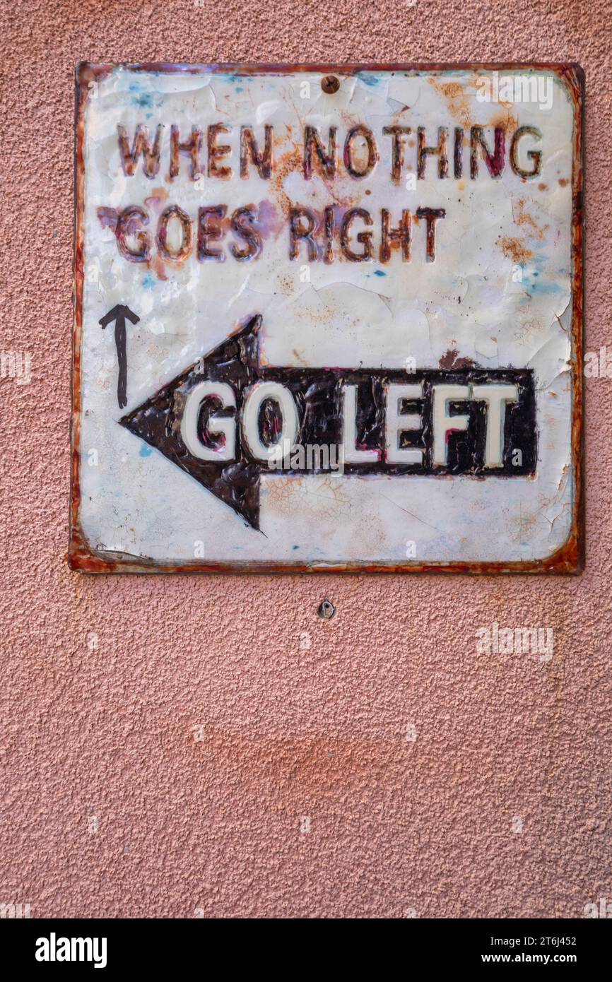 Vintage direction board hanging on pink wall with funny lettering hi ...