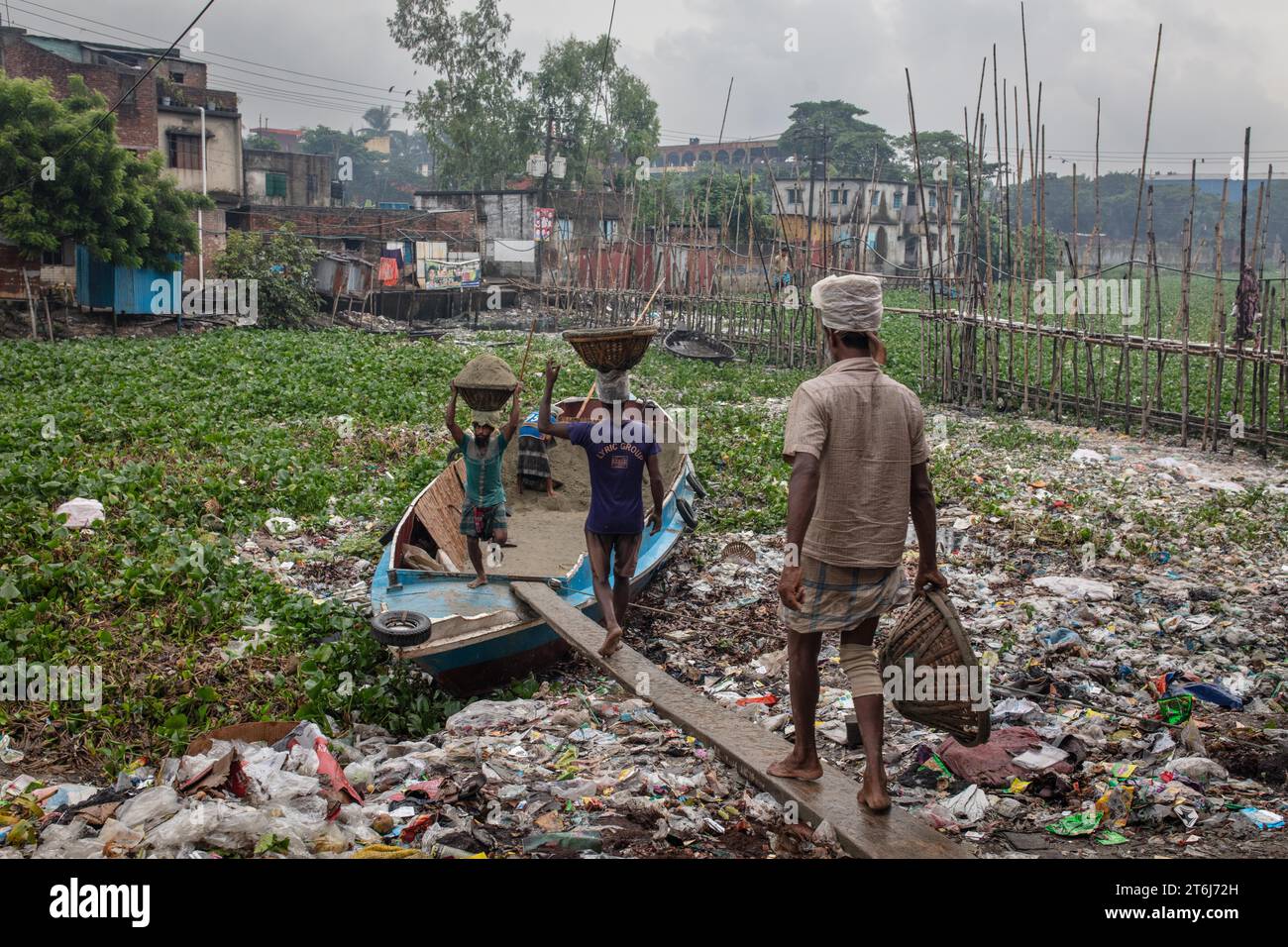 Construction workers transporting sand from a boat over a plank, Tel ...