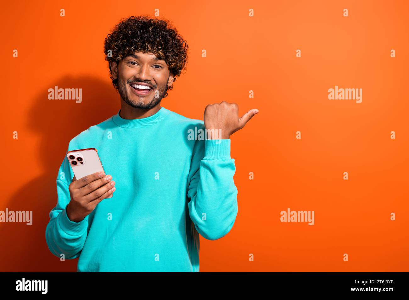 Portrait of arabian young guy direct finger empty space with smartphone ...
