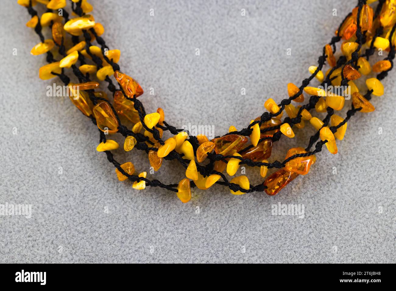 A polished amber necklace elegantly threaded on a black cord. The ...