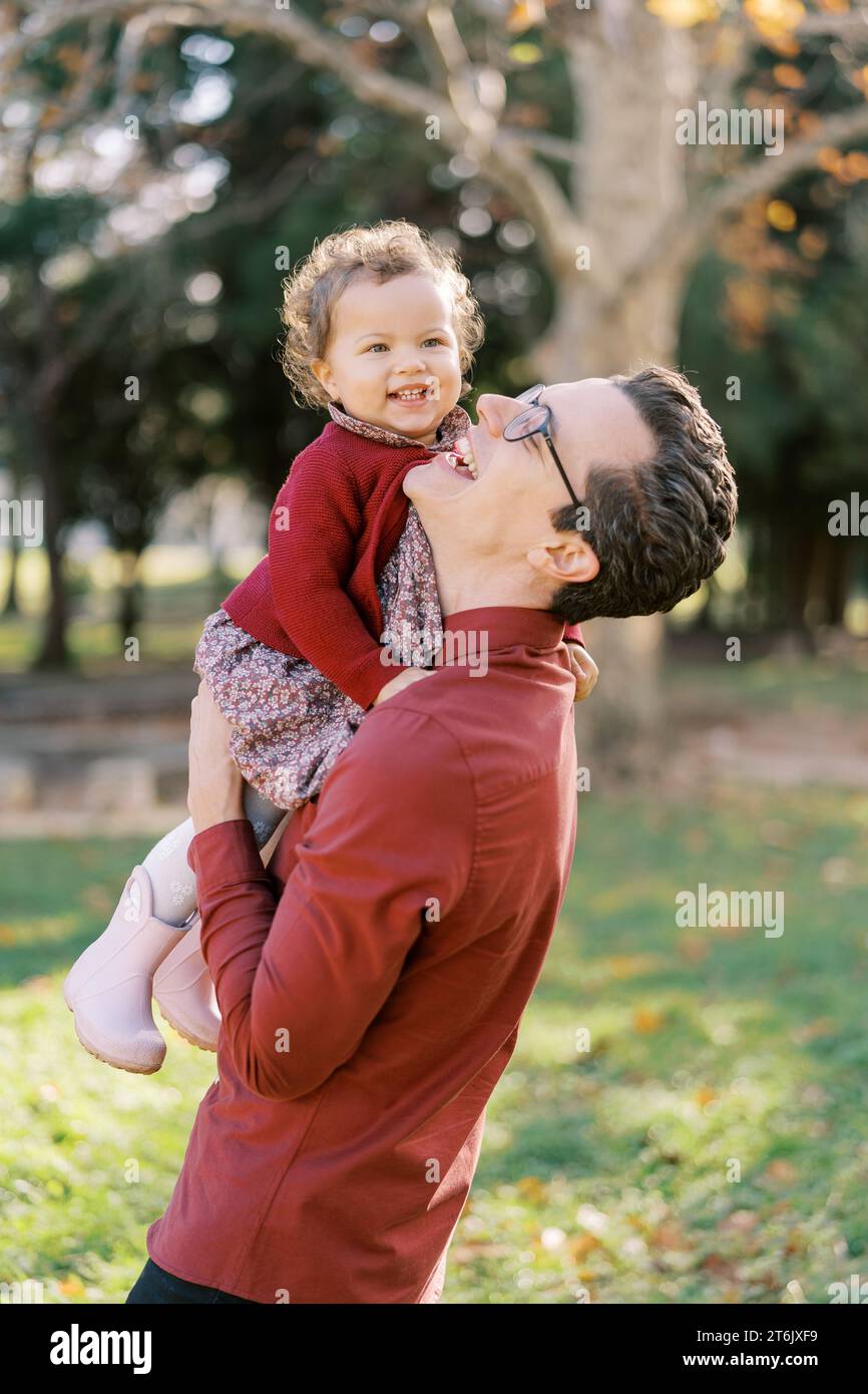 Laughing dad lifts high little girl hugging his neck Stock Photo - Alamy
