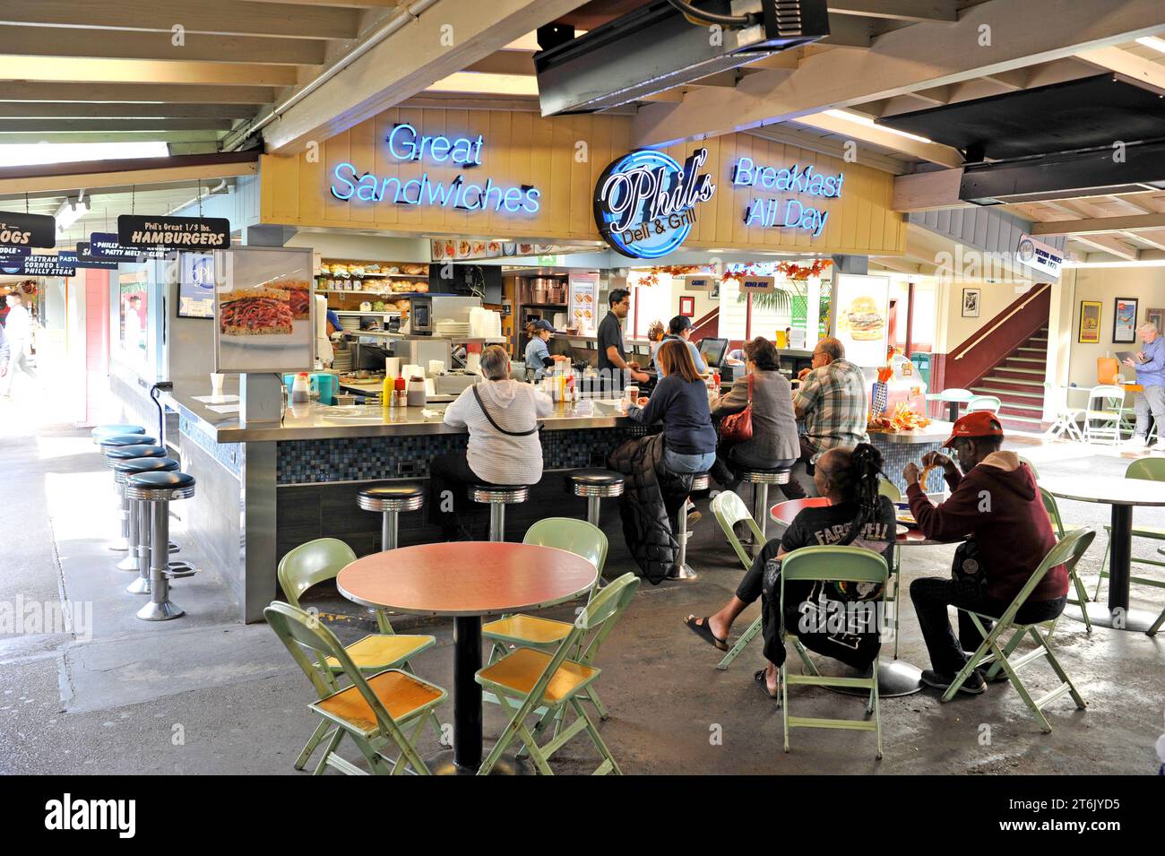 People dining at Phil's Deli, a small restaurant with a counter and ...