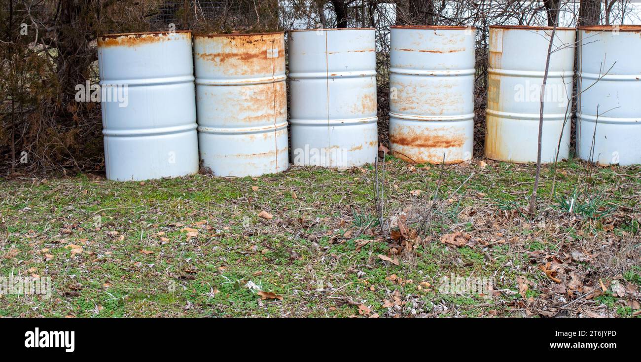 Round storage containers stand side by side on a back yard. The barrels ...