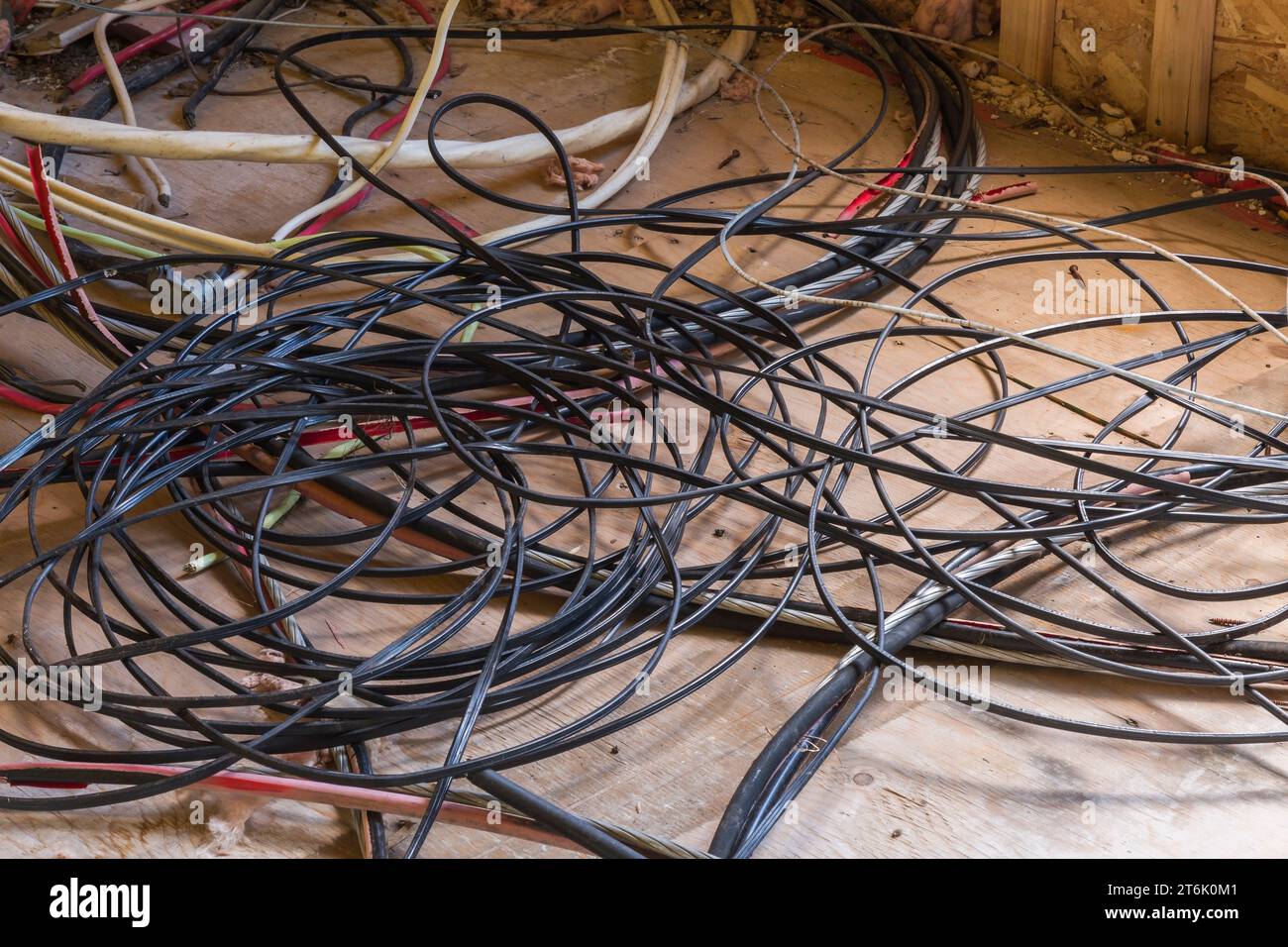 Cables and wiring on plywood floor inside abandoned commercial building ...