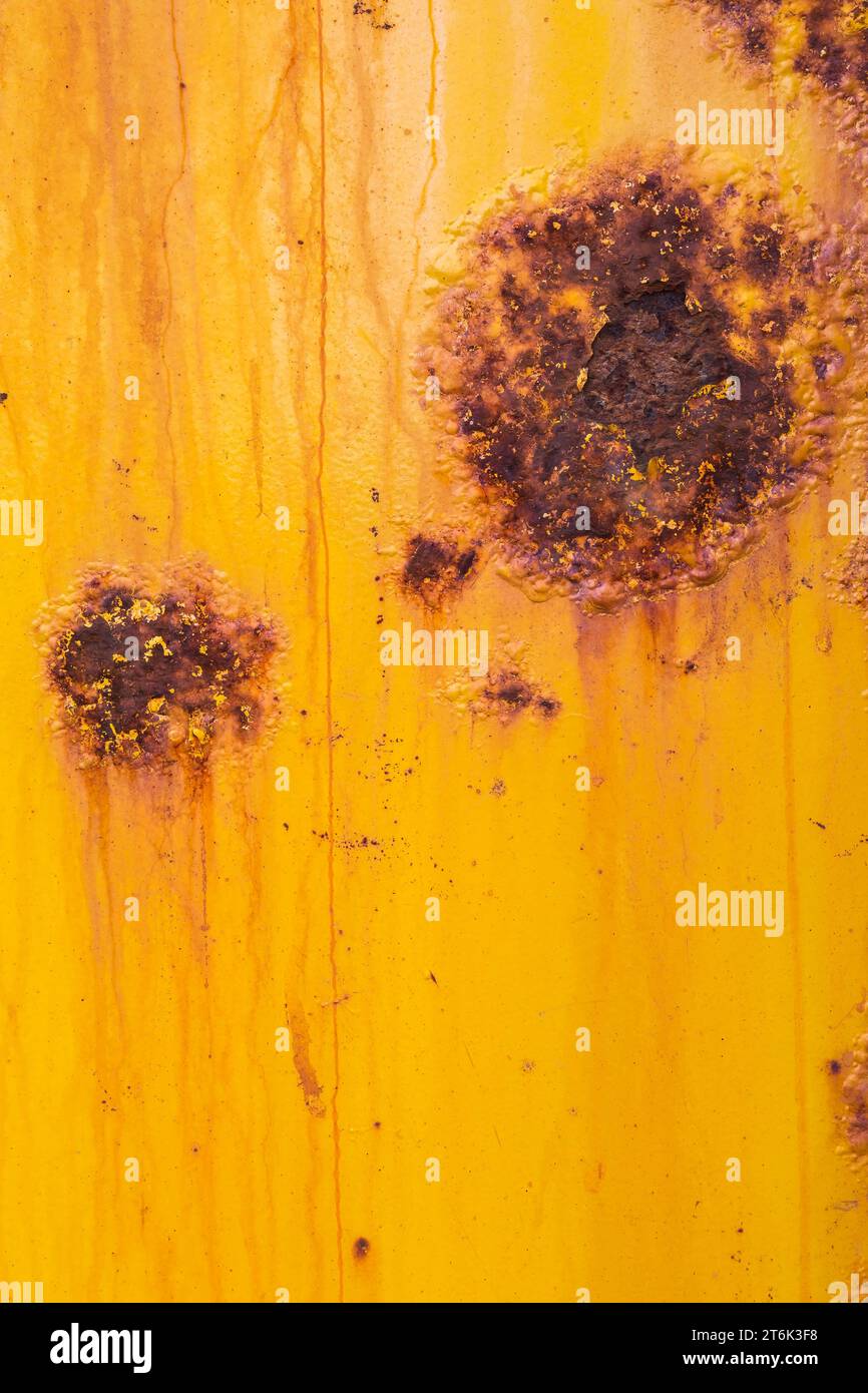 Rust spots and stains on side wall of old yellow metal waste container ...