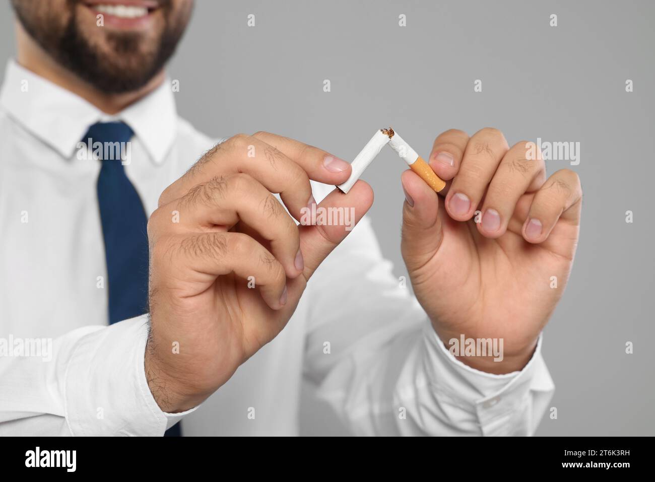 Stop smoking concept. Man breaking cigarette on light grey background ...