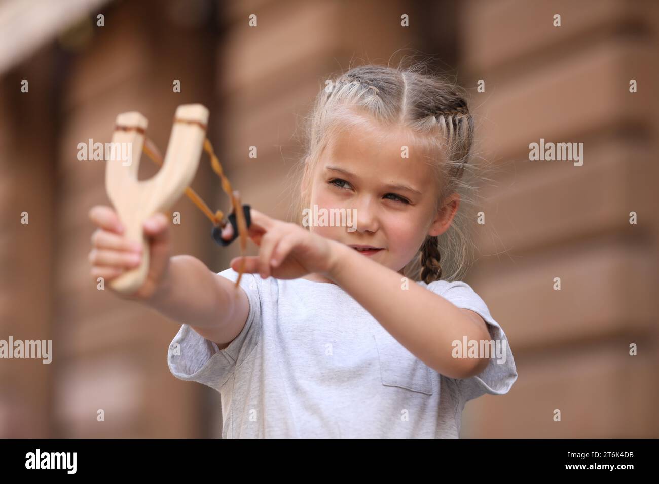 Little girl playing with slingshot on city street Stock Photo - Alamy