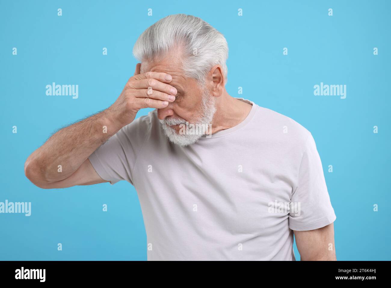 Embarrassed senior man covering eyes on light blue background Stock ...