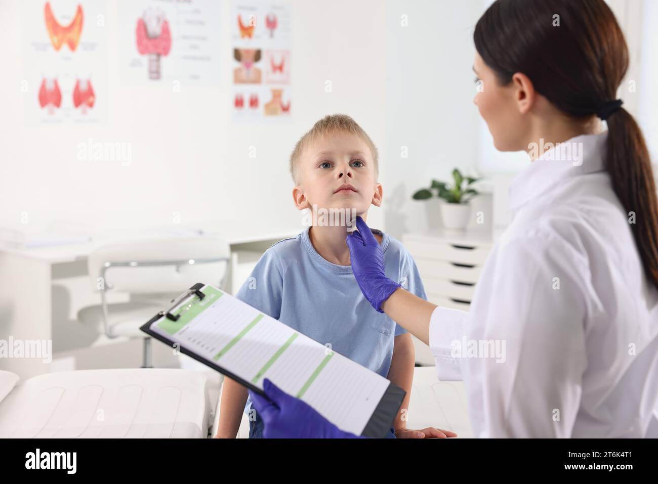 Endocrinologist with clipboard examining boy's thyroid gland at ...