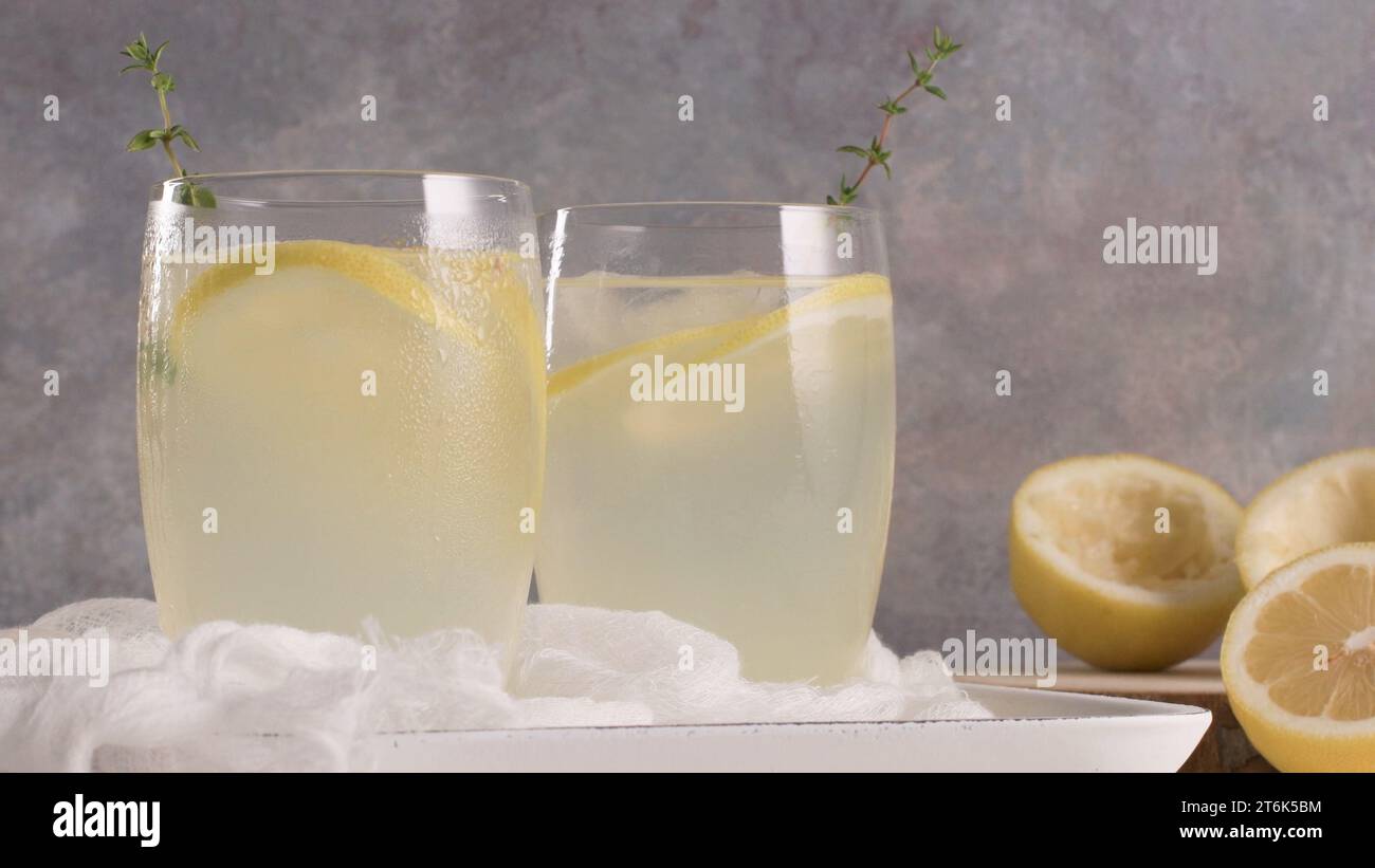 Cold lemonade or alcoholic cocktail with lemon, rosemary and ice in ...