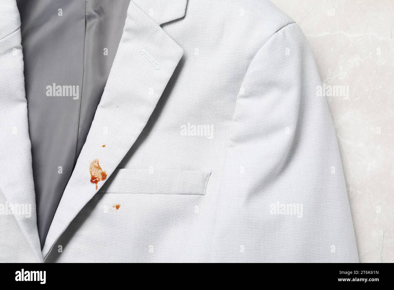 Dirty jacket with stain of sauce on light grey marble table, top view ...