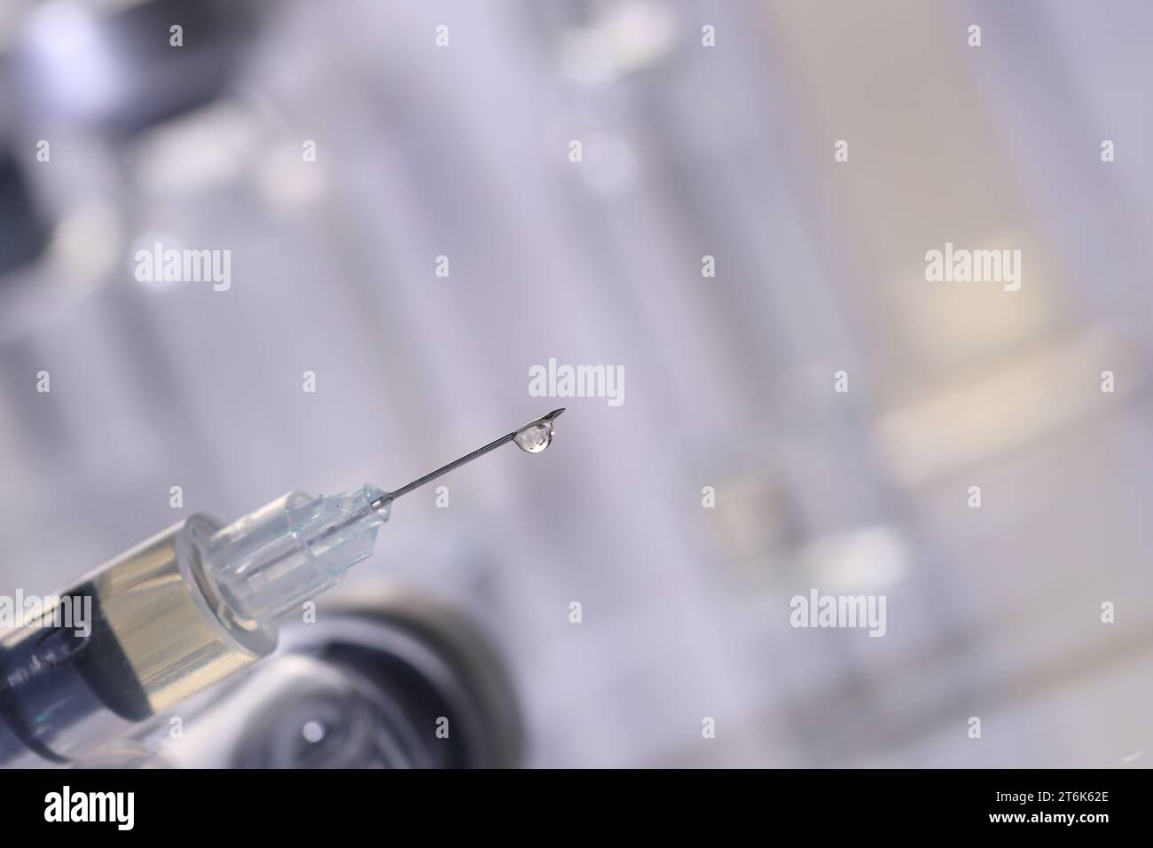 Drop of medication on syringe needle against blurred background ...