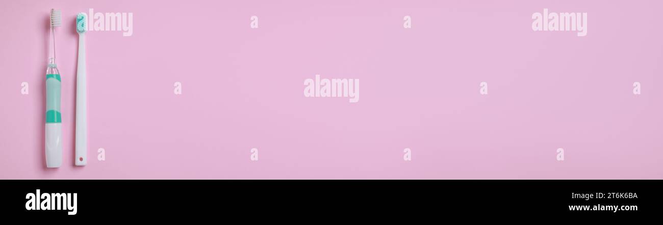Electric and plastic toothbrushes on pink background, top view. Banner ...