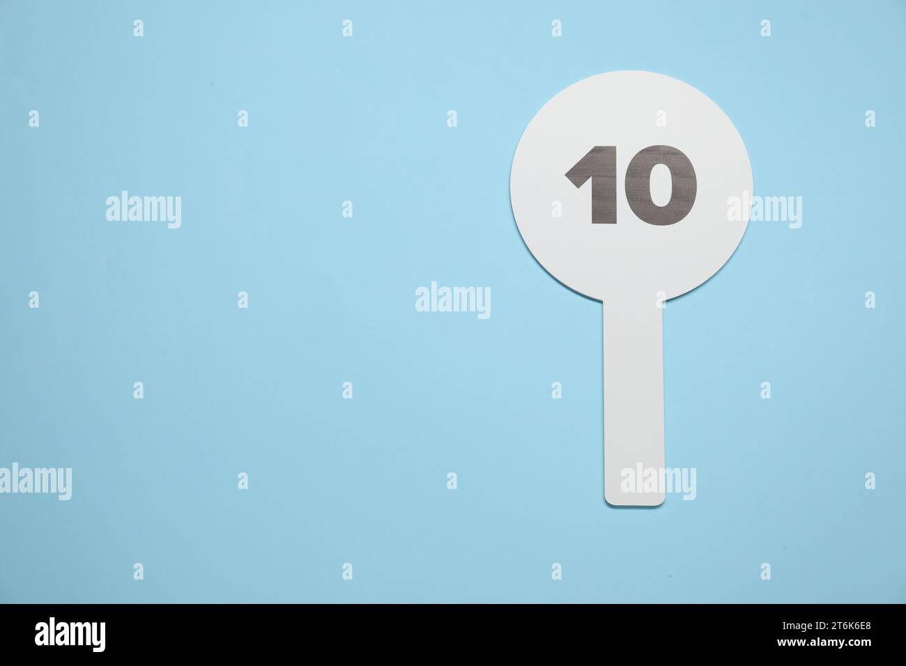 Auction paddle with number 10 on light blue background, top view. Space ...