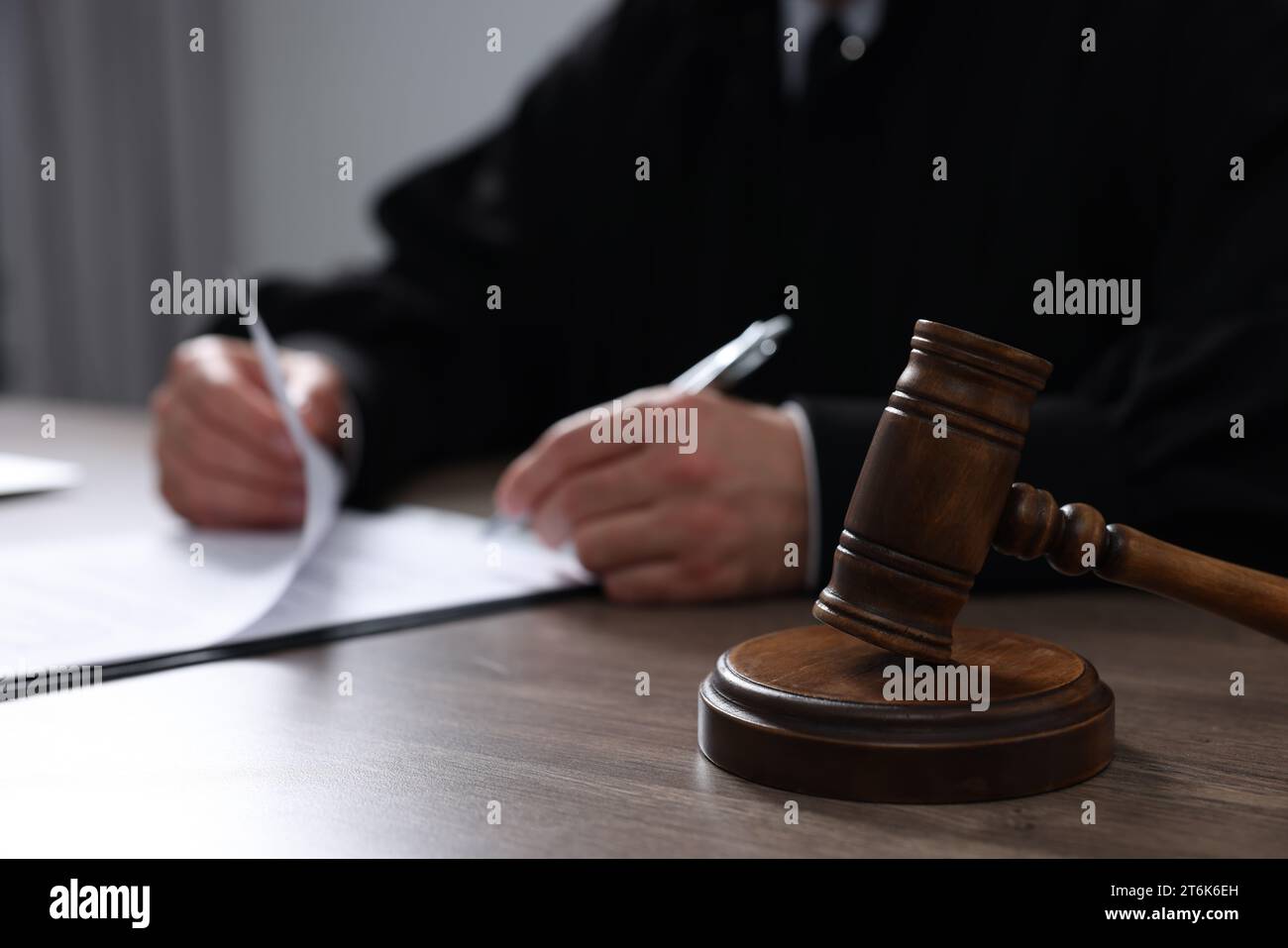 Judge with gavel writing in papers at wooden table, closeup Stock Photo ...