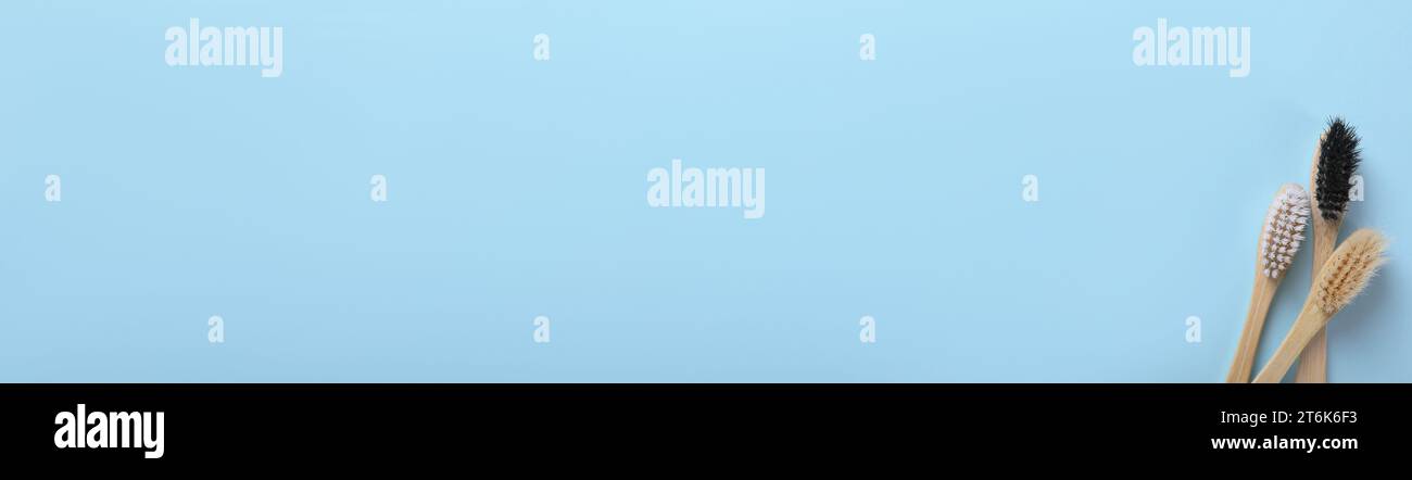 Bamboo toothbrushes on light blue background, flat lay. Banner design ...