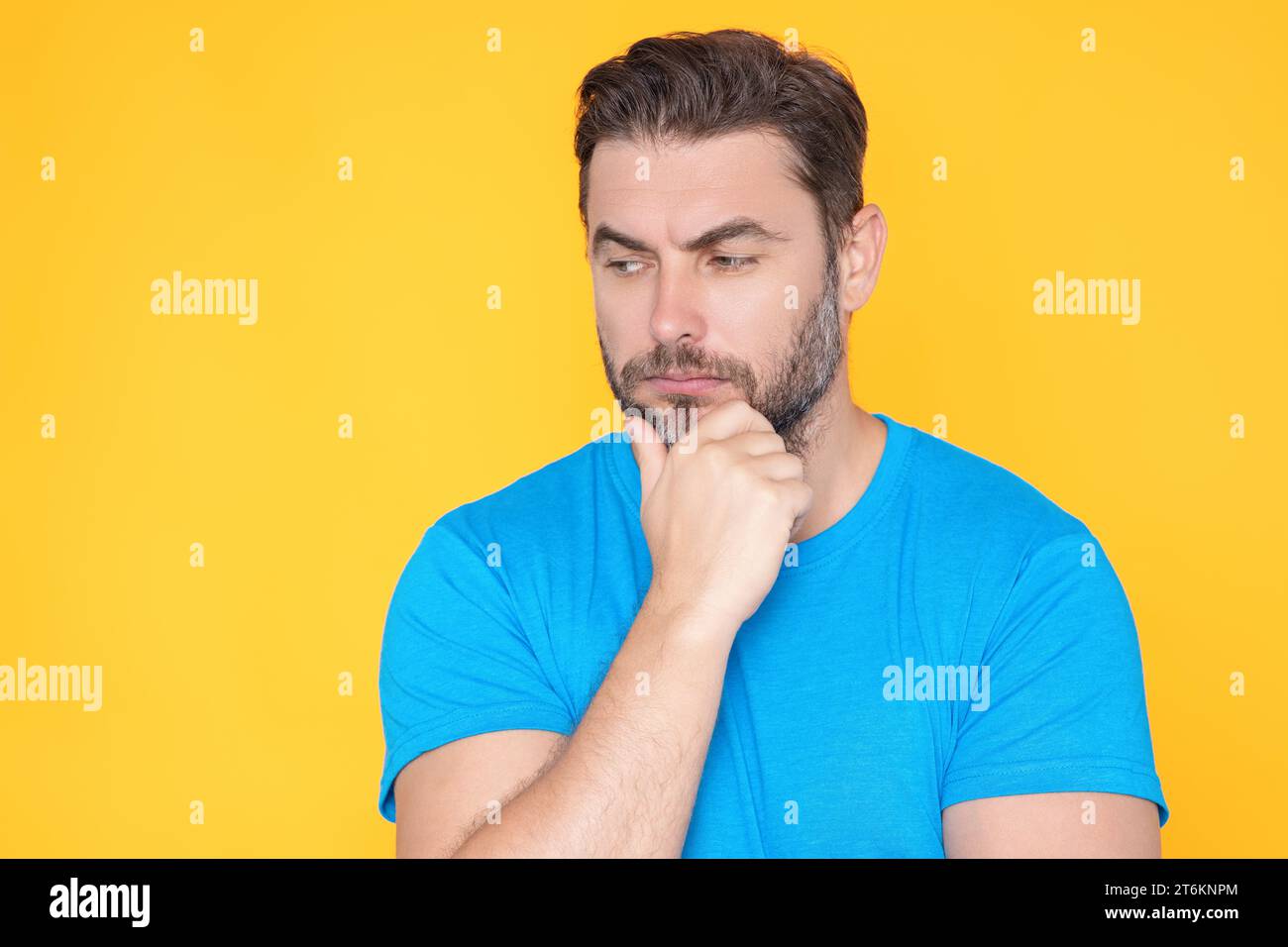 Handsome man standing over yellow background with hand on chin thinking ...