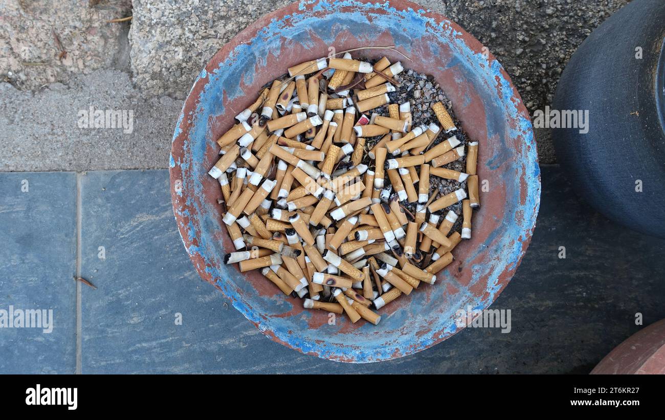 Olbia, Sardinia, Italy, July 29, 2021. Plant pot used as ashtray full of cigarette butts and ...