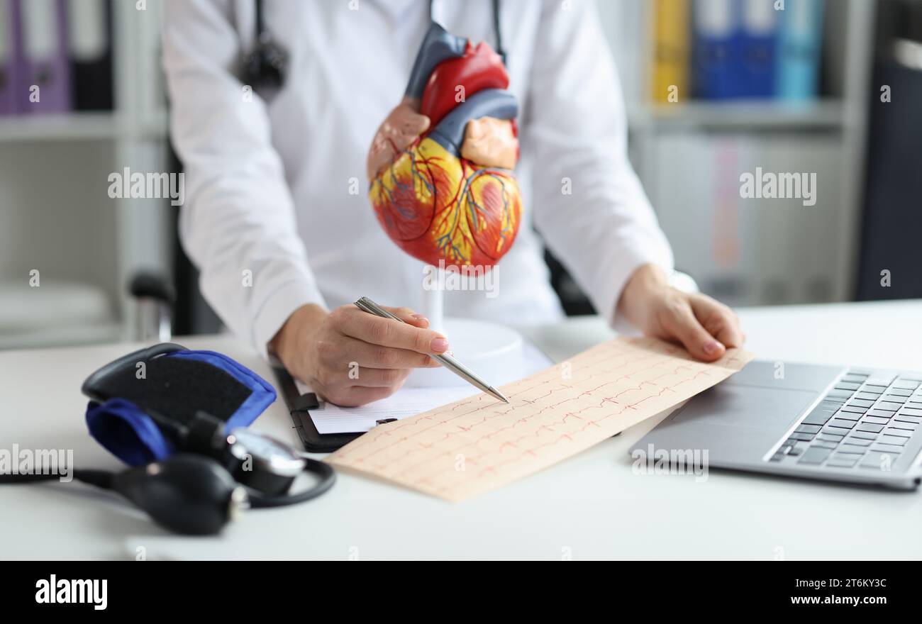 Doctor cardiologist examines electrocardiogram of patient heart in ...
