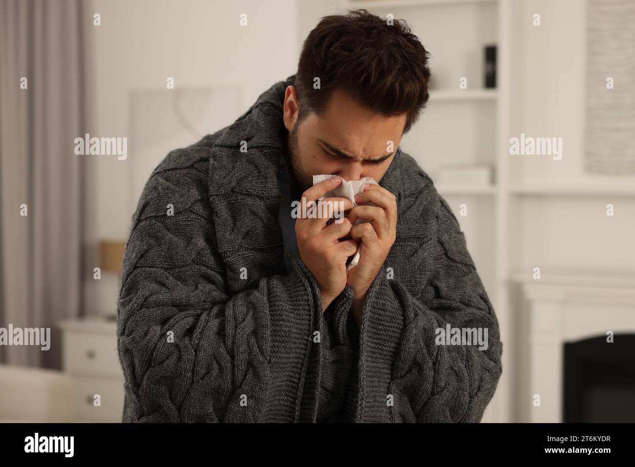 Sick man wrapped in blanket with tissue blowing nose at home. Cold ...