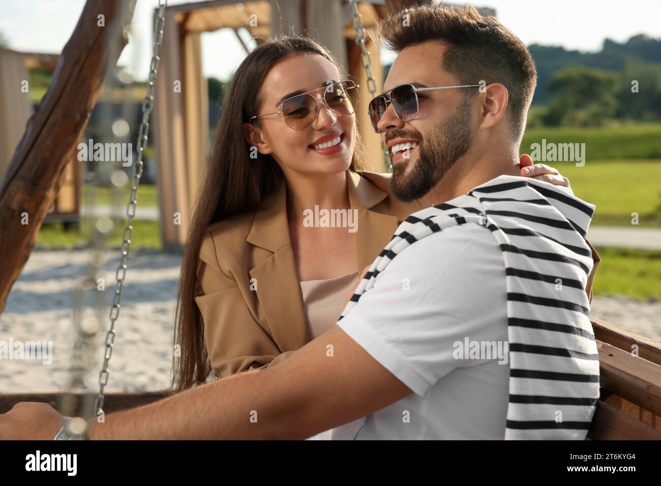Romantic date. Beautiful couple spending time together on swing bench ...