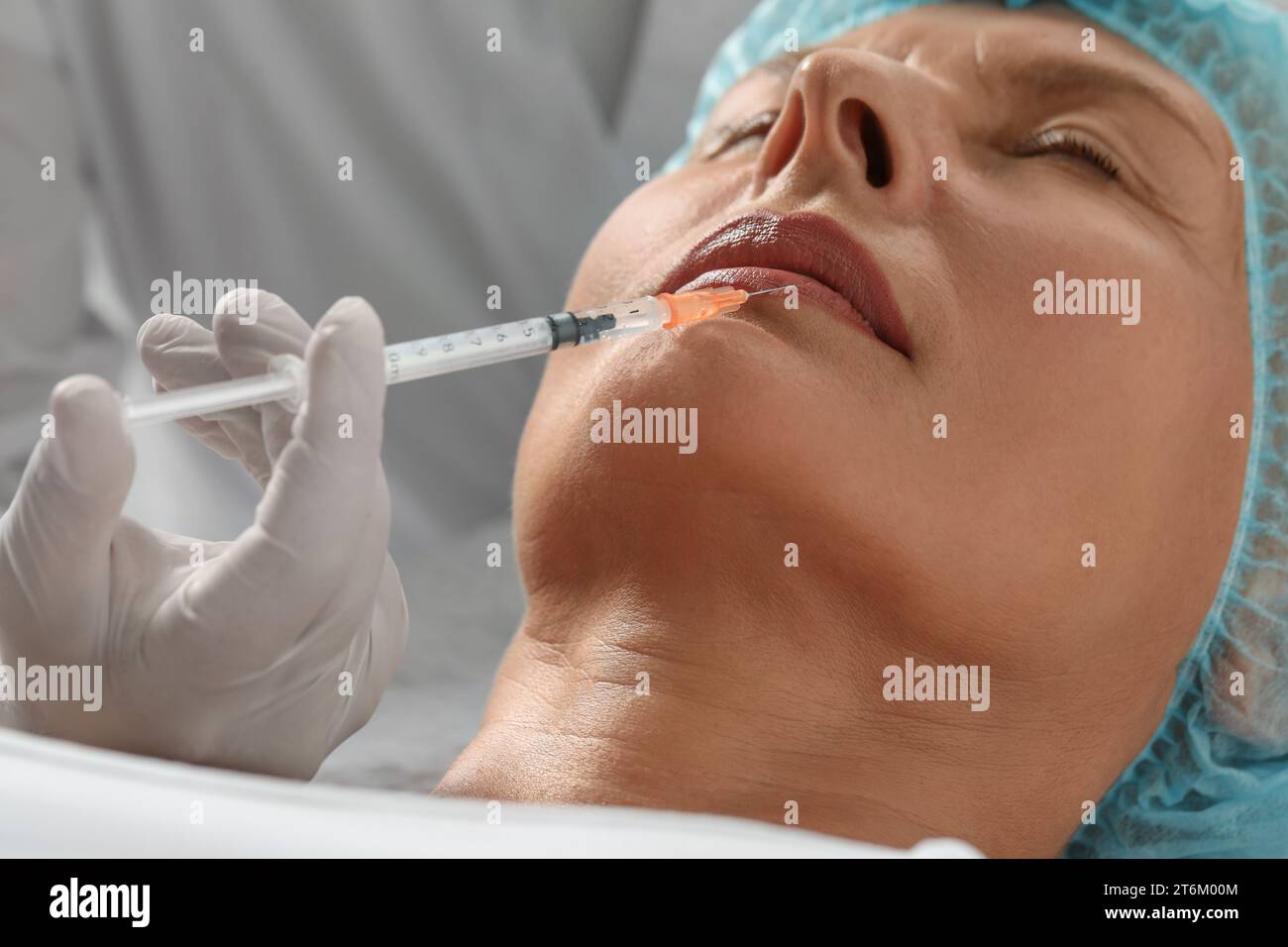 Doctor giving lips injection to senior woman in clinic, closeup ...