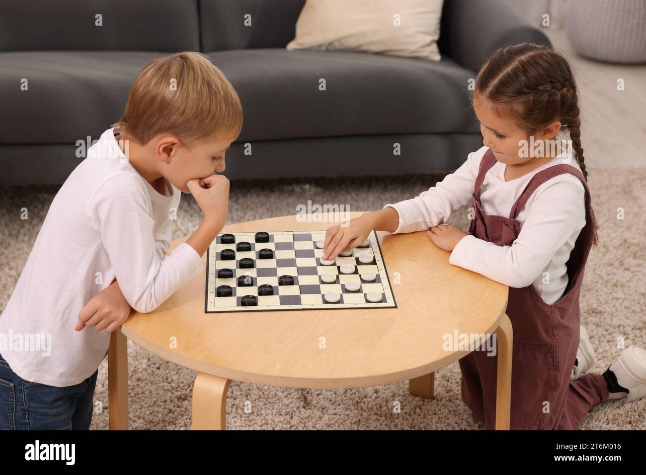 Children playing checkers at coffee table indoors Stock Photo - Alamy