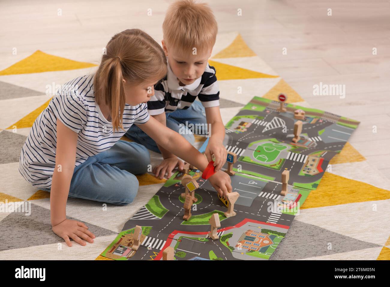 Little children playing with set of wooden road signs and toy cars ...