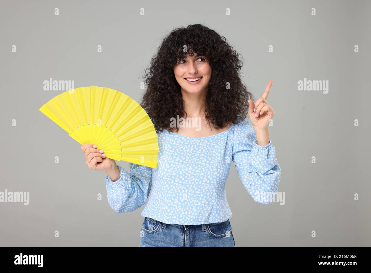 Happy woman holding hand fan on light grey background Stock Photo - Alamy
