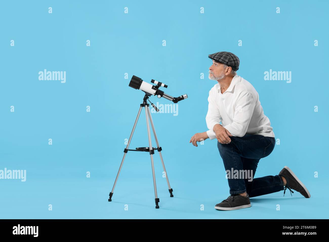 Senior astronomer with telescope on light blue background Stock Photo ...