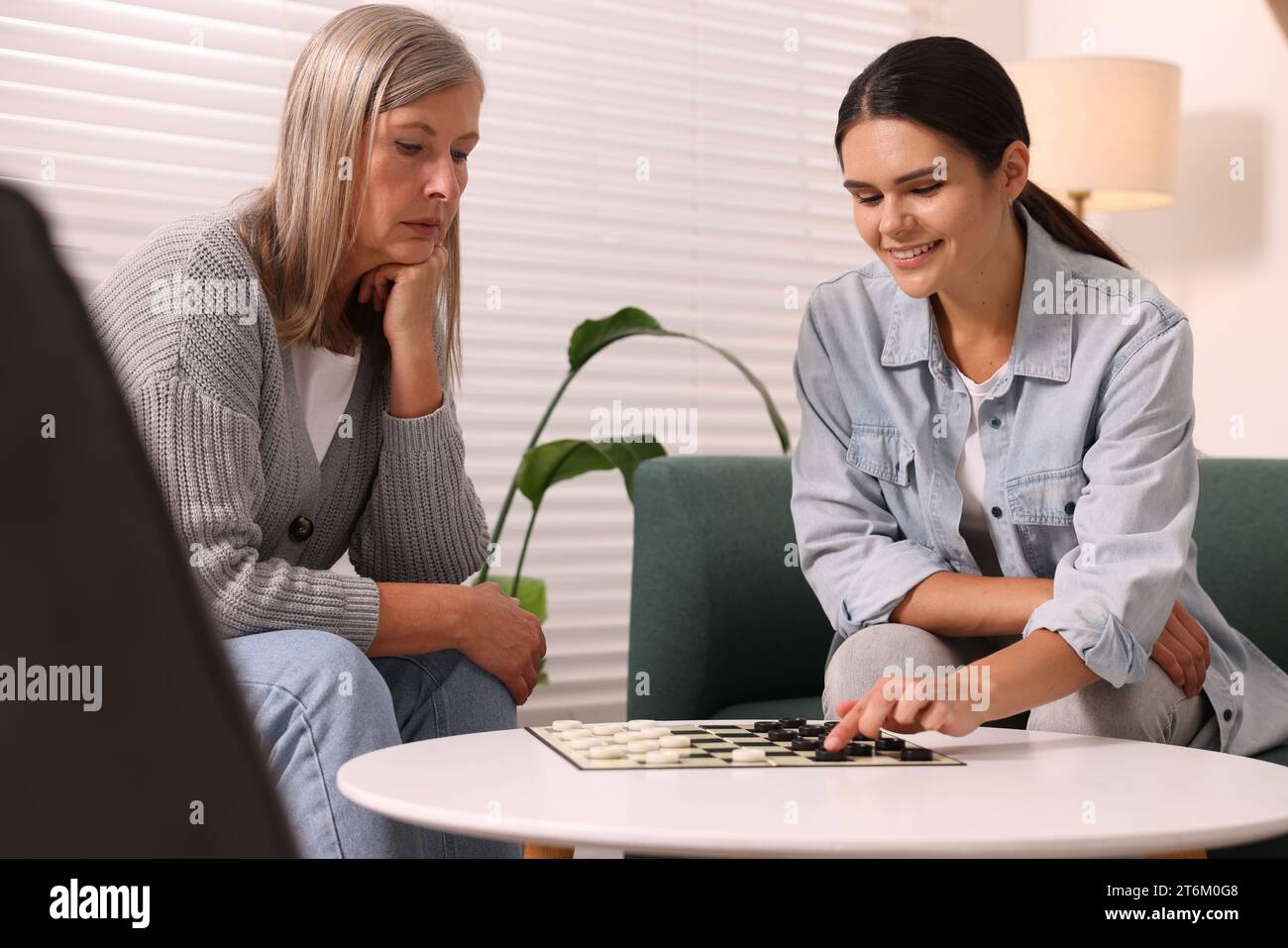 Women playing checkers at coffee table in room Stock Photo - Alamy