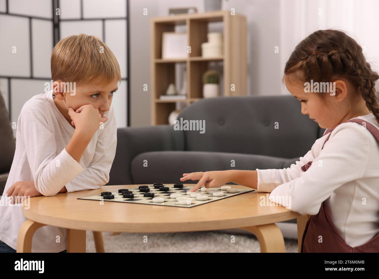 Children playing checkers at coffee table in room Stock Photo - Alamy
