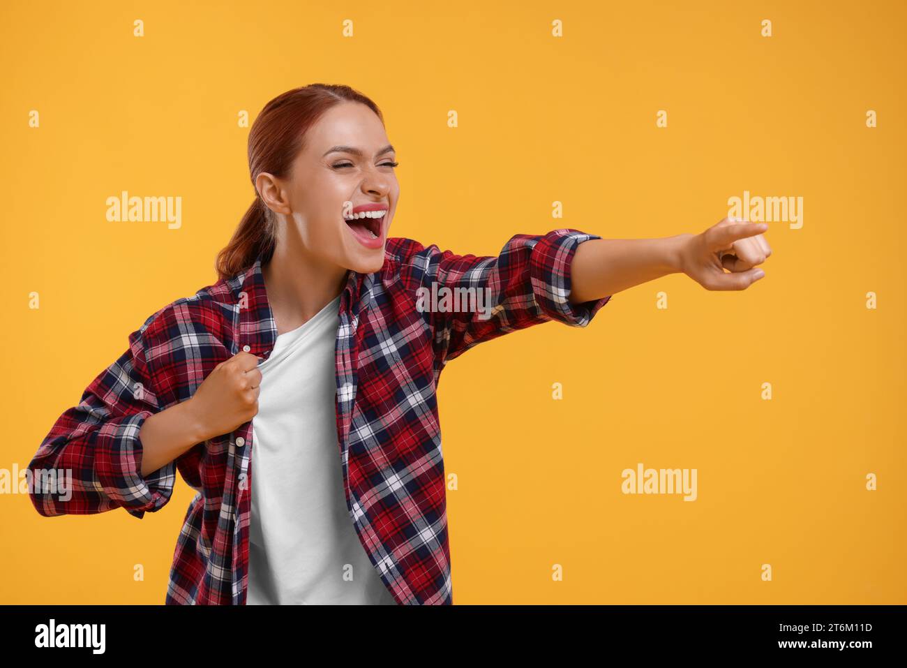 Emotional fan pointing at something on yellow background Stock Photo ...
